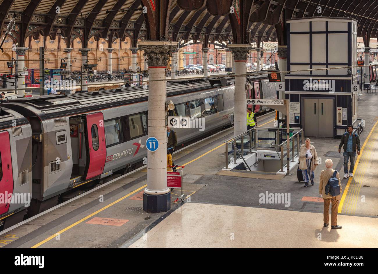 A train rests at a railway station platform under a historic canopy ...
