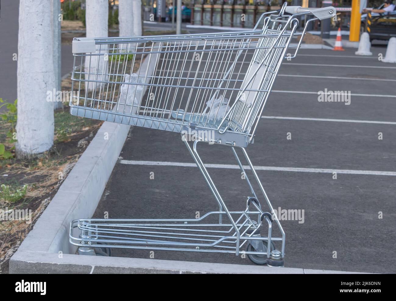 Empty shopping cart in grocery store parking lot with plastic bags ...