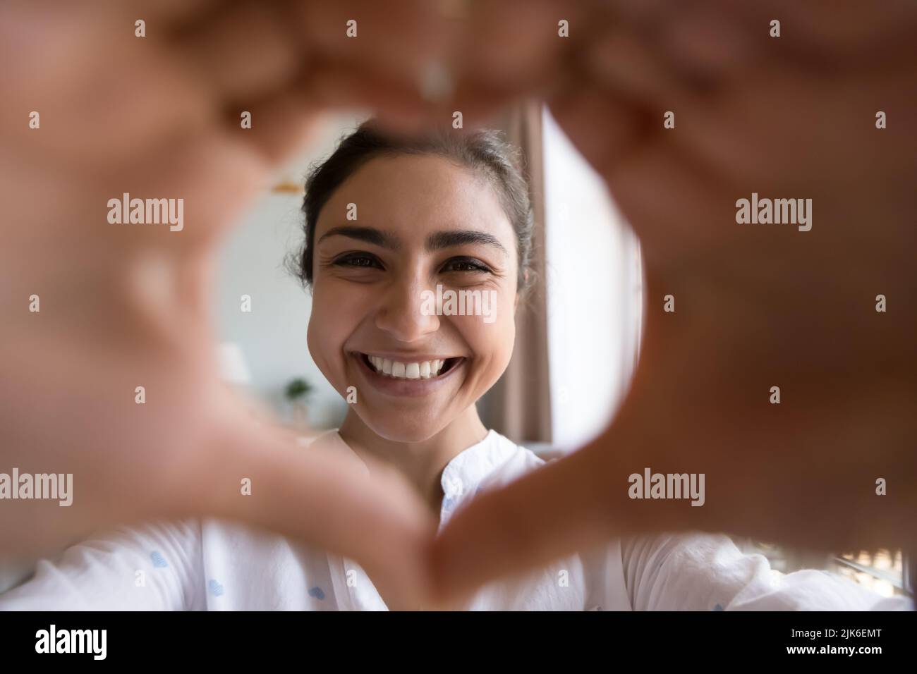 Cheerful young Indian woman face through hand heart shaped frame Stock ...