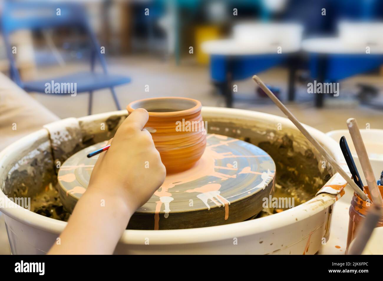 Kid painting ceramic pot on a Potter's wheel at workshop. Hobbies ...