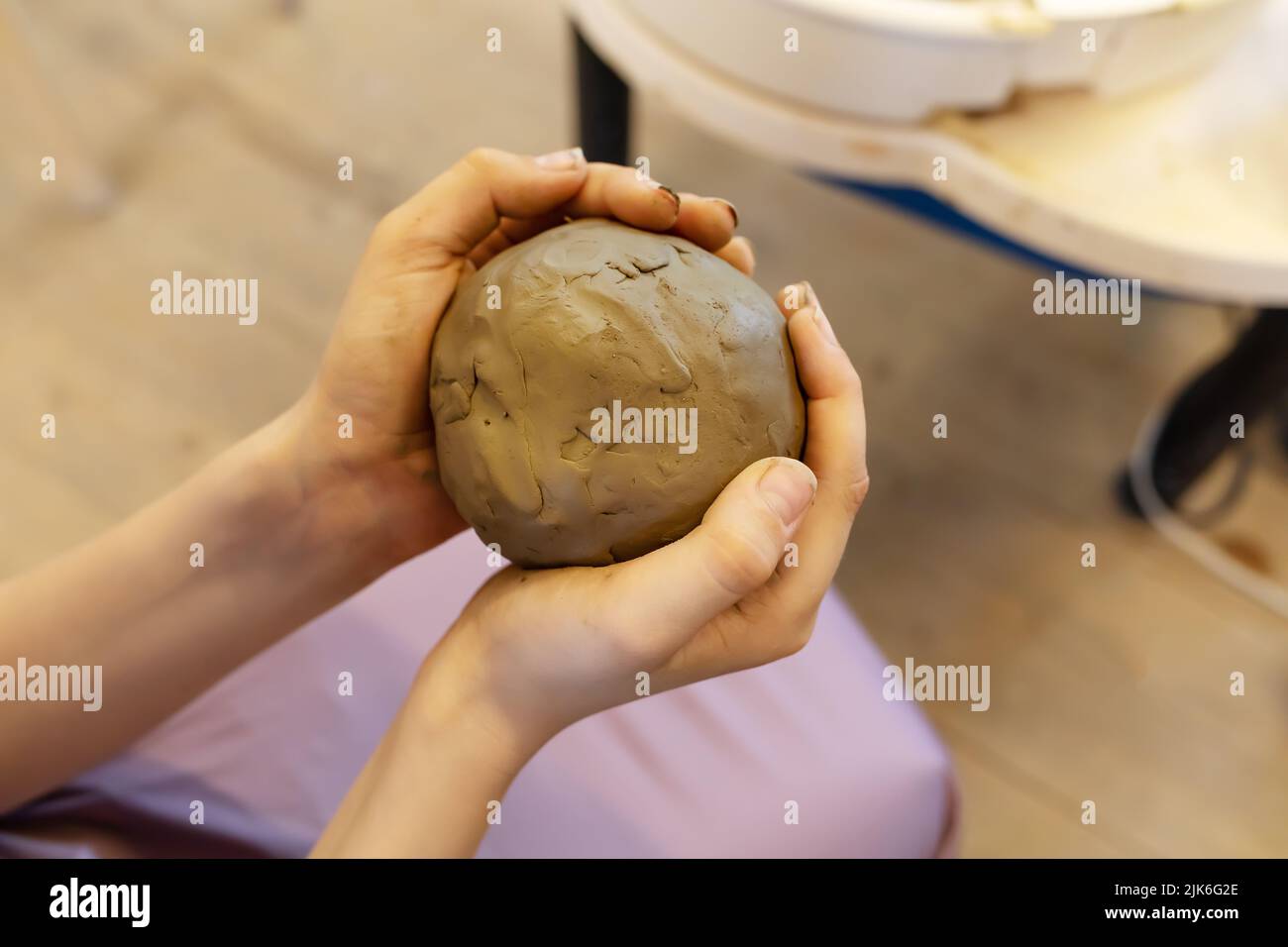 A child crushes a large piece of clay for modeling with his hands near ...
