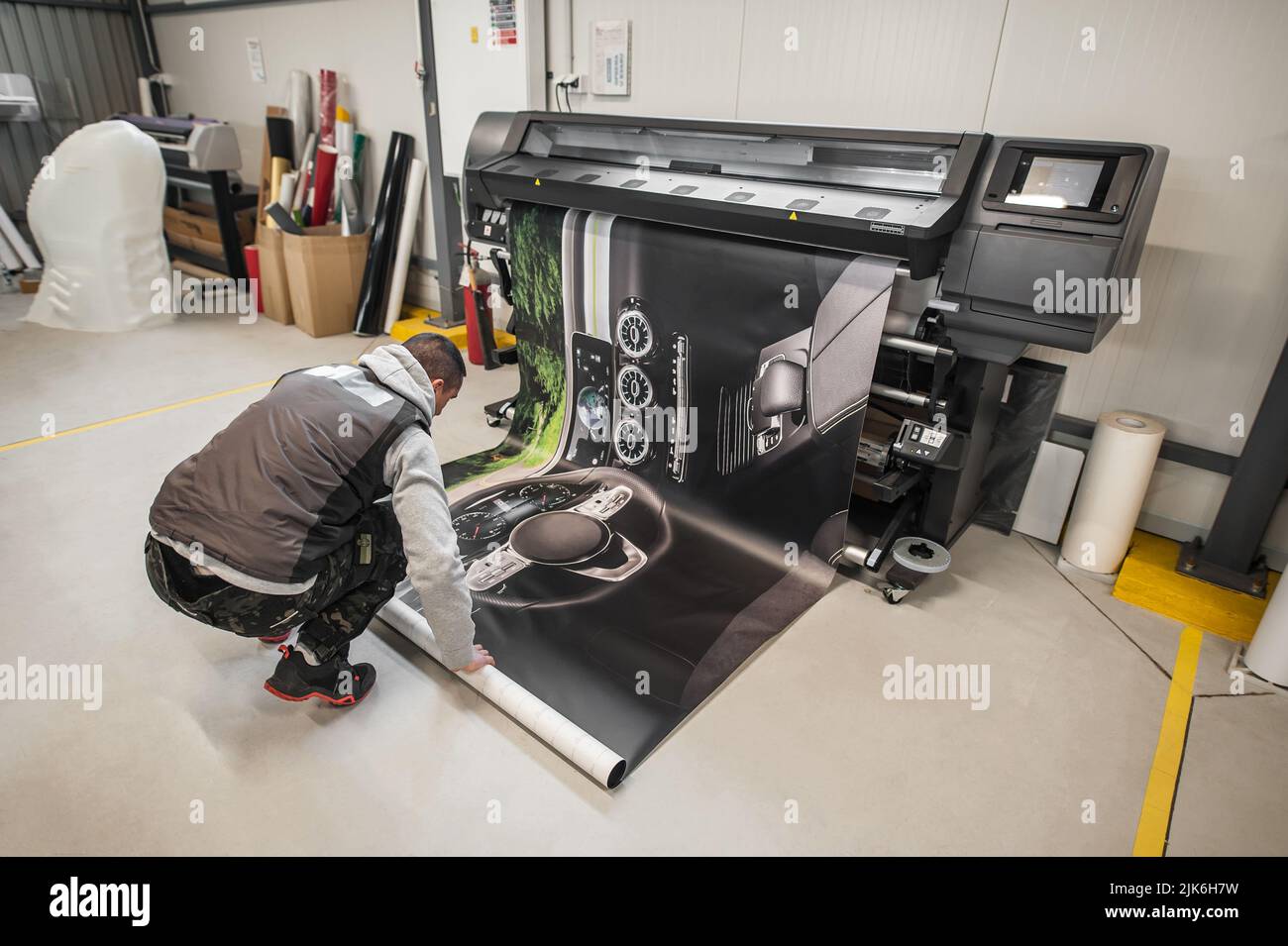 Technician worker operator works on large premium industrial printer ...