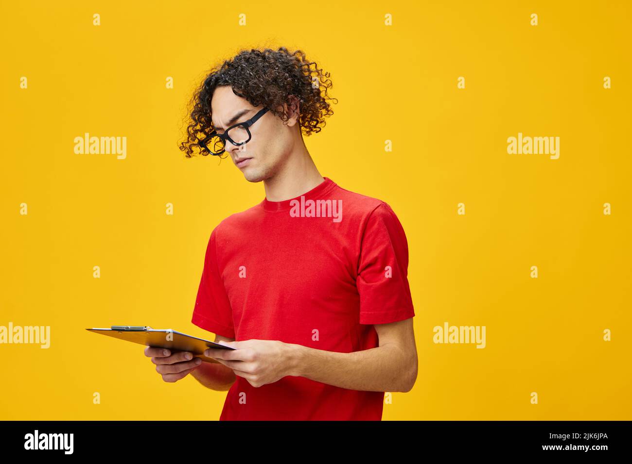 Thinking myopic young student man in red t-shirt funny eyewear holds ...