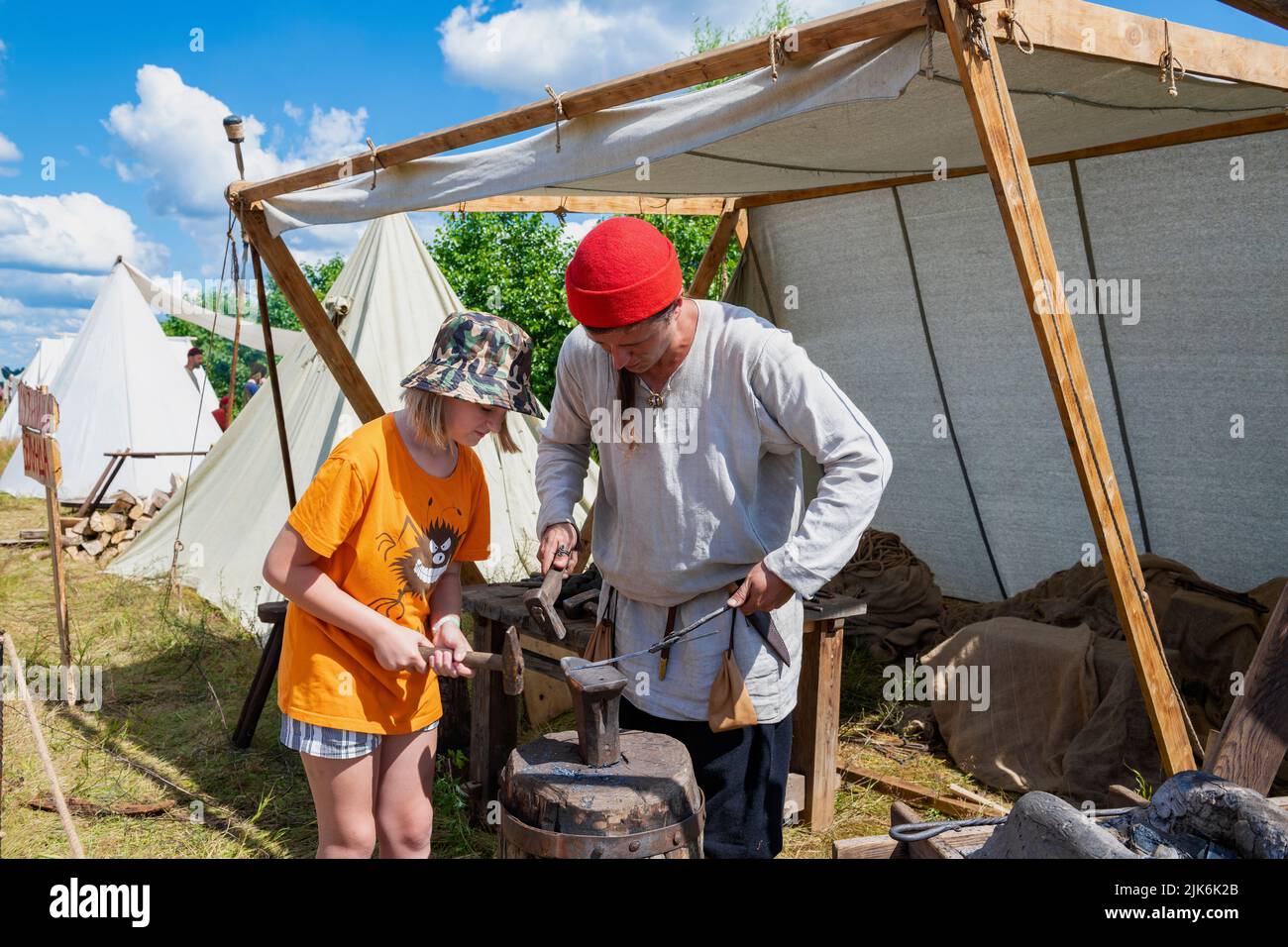 TVER REGION, RUSSIA - JULY 22, 2022: A blacksmith shows a teenage girl ...