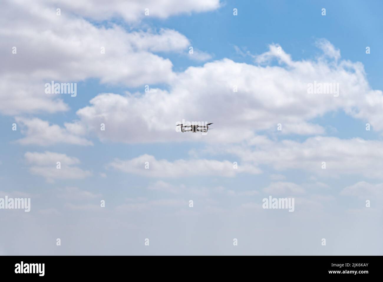 Small grey drone in blue sky with clouds Stock Photo - Alamy