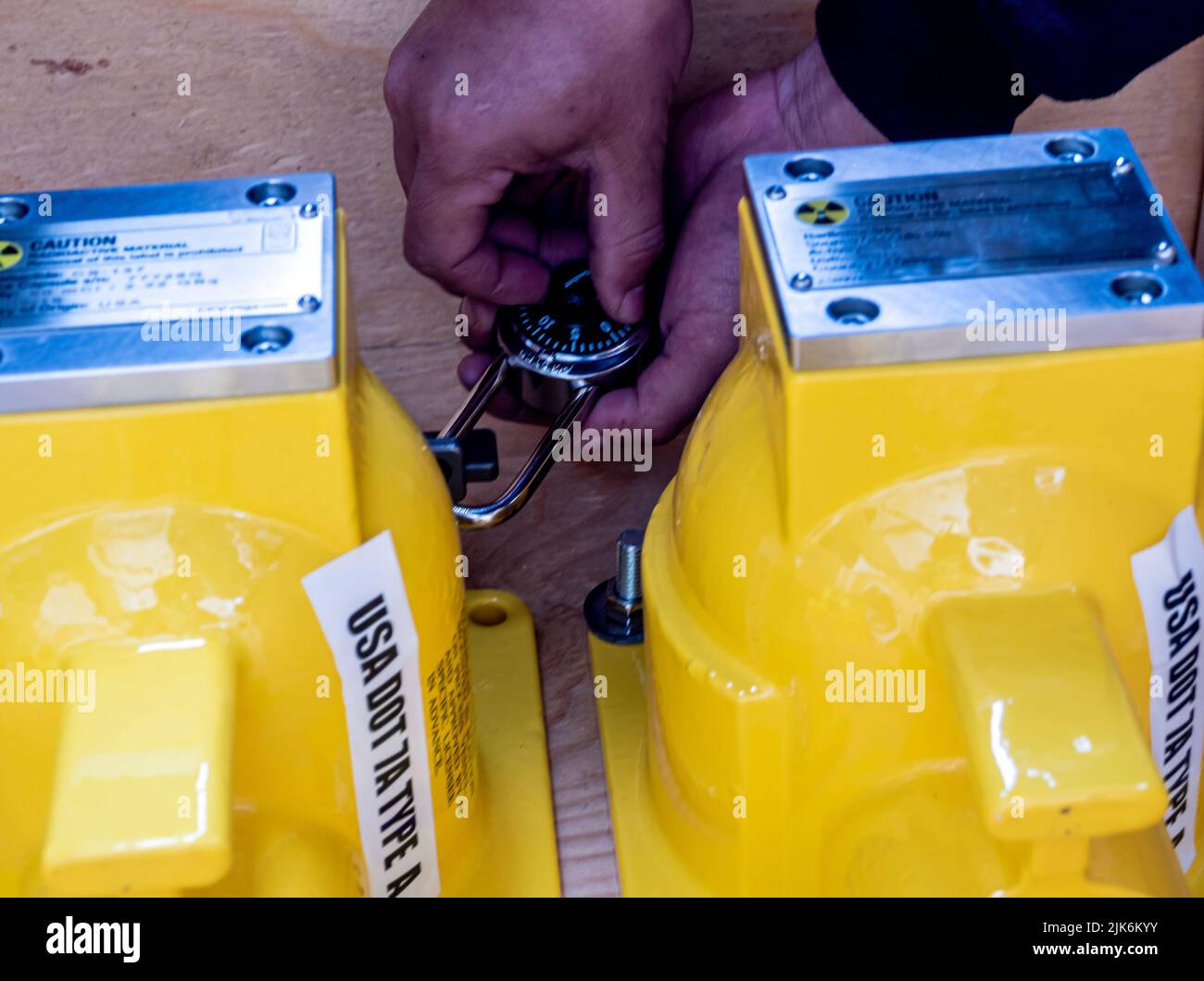 The worker spins the padlock code to unlock the mechanical shutter of ...