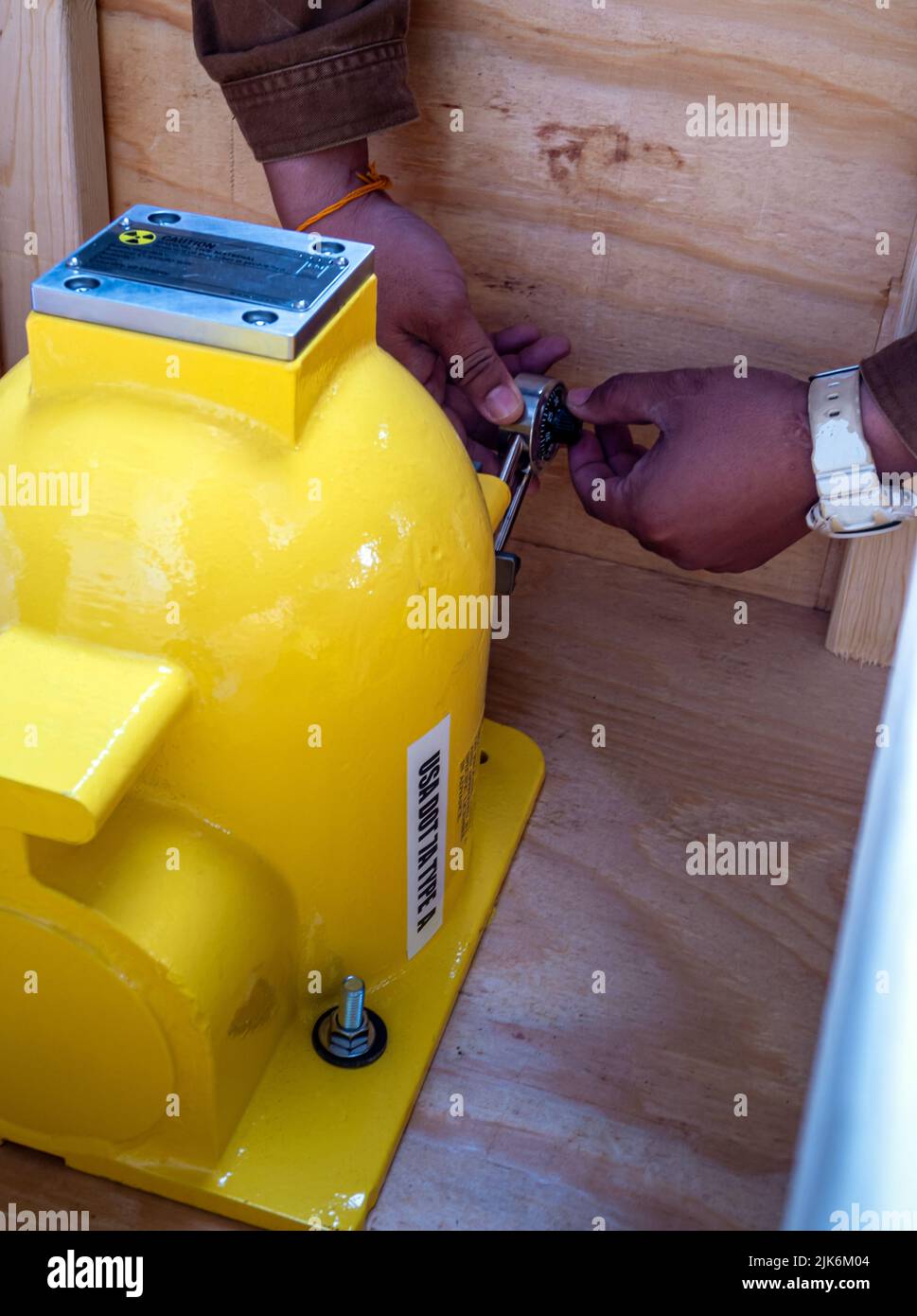 The worker spins the padlock code to unlock the mechanical shutter of ...