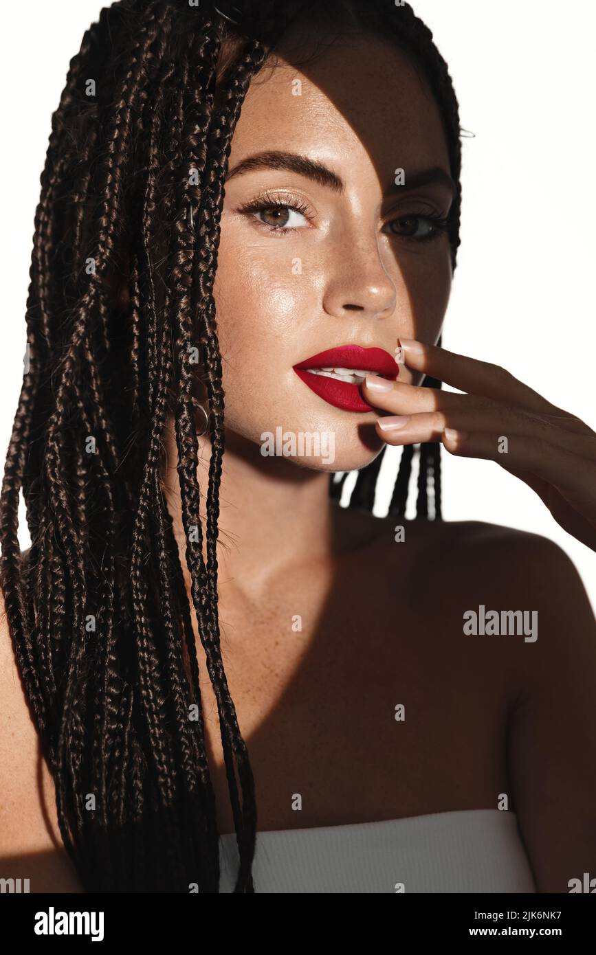 Make up and beauty. Vertical shot of young woman touches her red lips ...