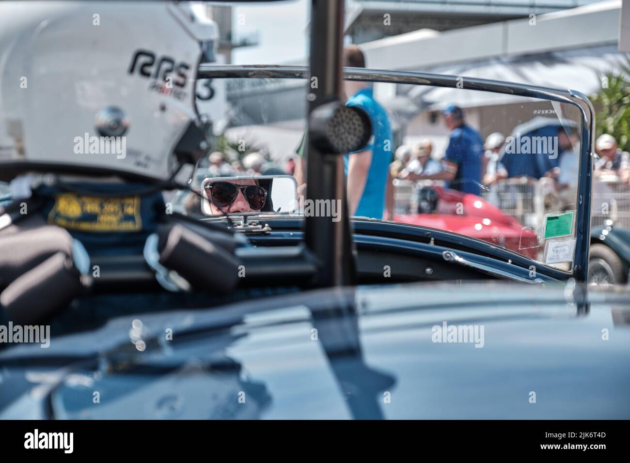 A driver sitting in his car seen from behind with his face reflected in ...