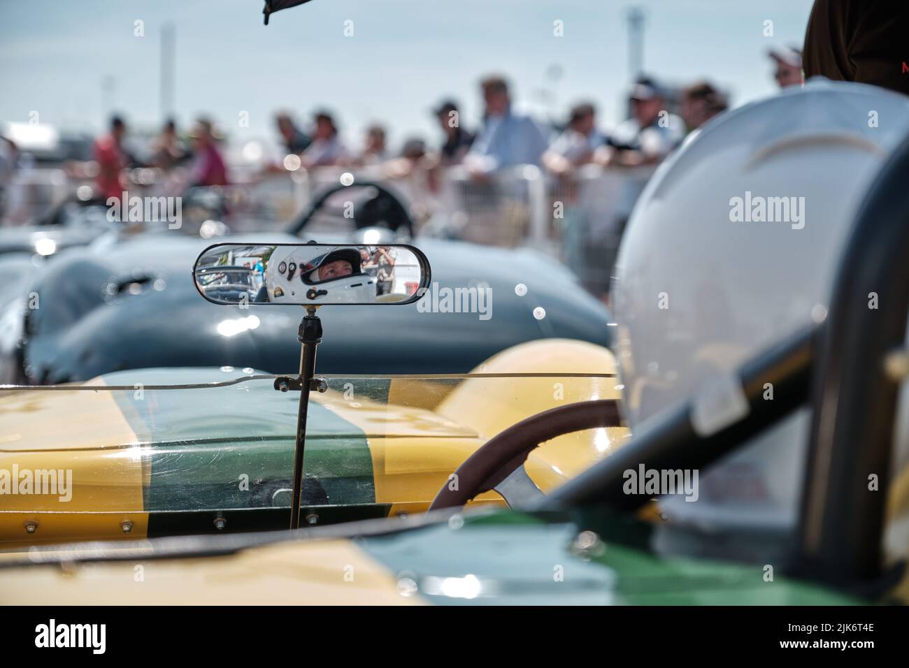 A group of people standing along the race track watching race cars ...