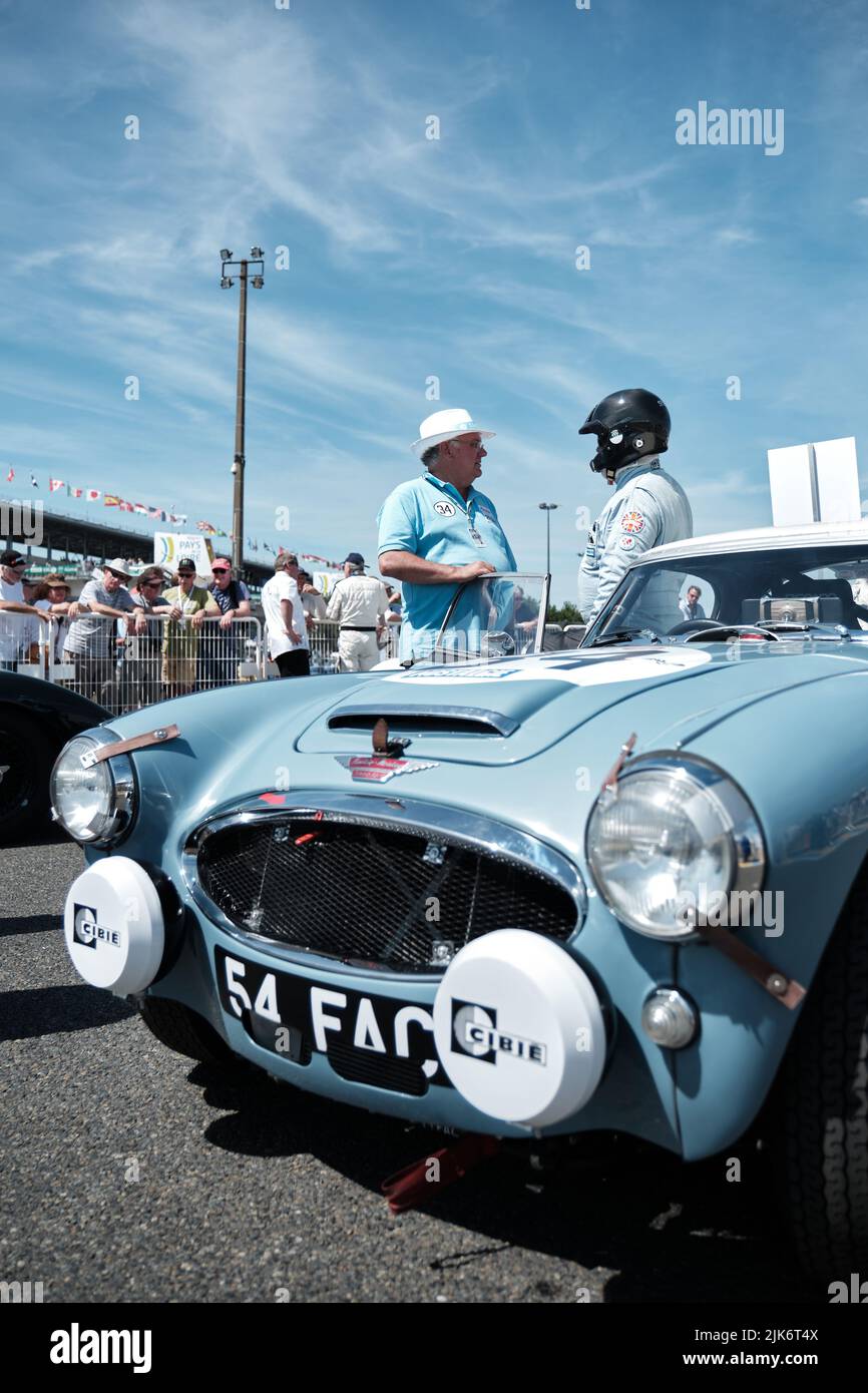 A race car driver is talking to a member of his team in front of his ...