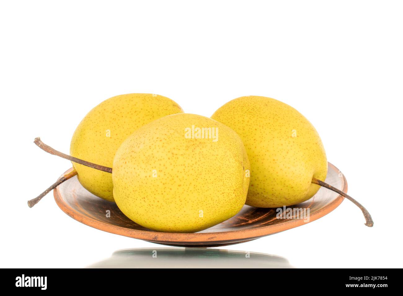 Three organic bright yellow pears on a clay plate, close-up, isolated ...