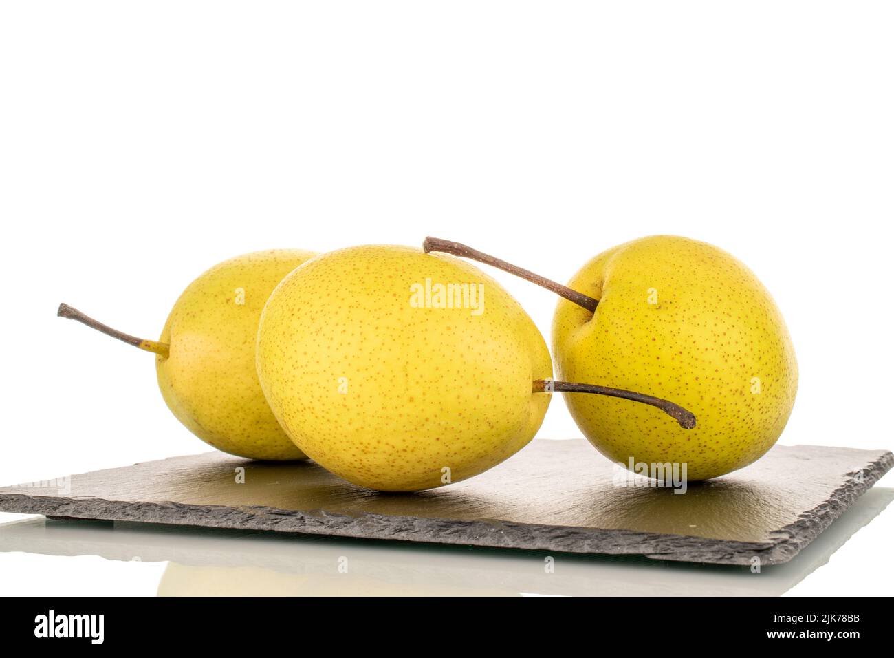 Three sweet bright yellow pears on a slate stone, close-up, isolated on ...