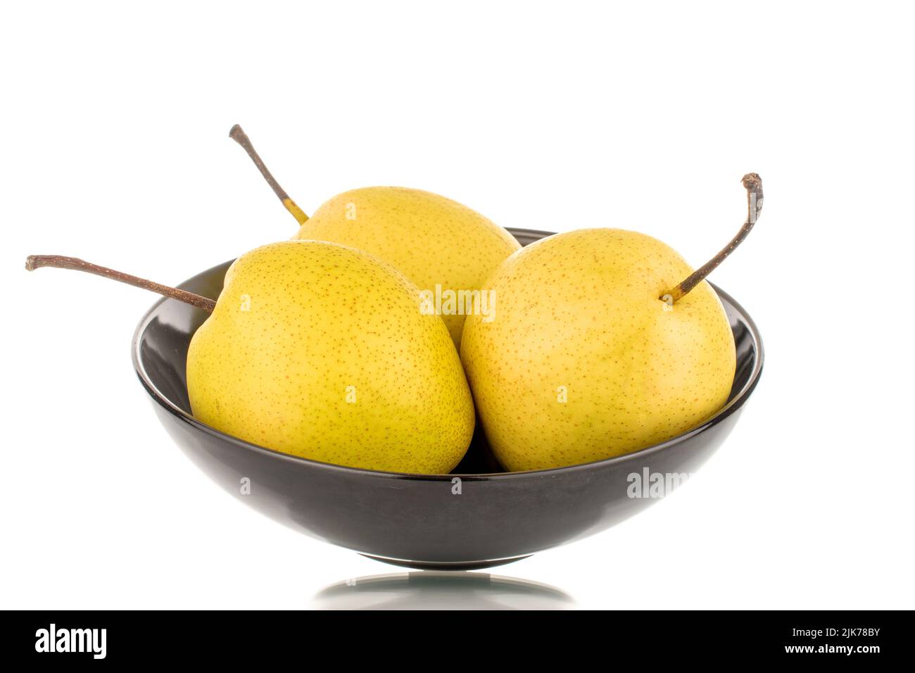 Three organic bright yellow pears on a ceramic plate, close-up ...