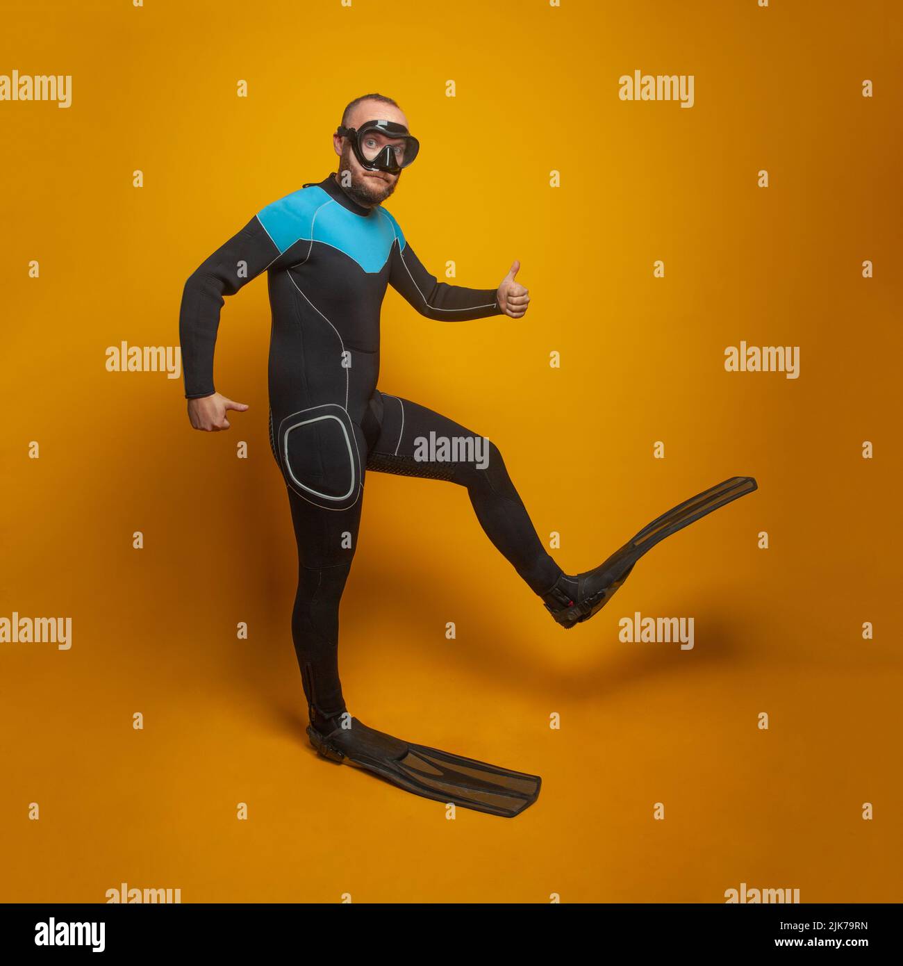 Happy scuba diver diving man going to the side against bright orange ...