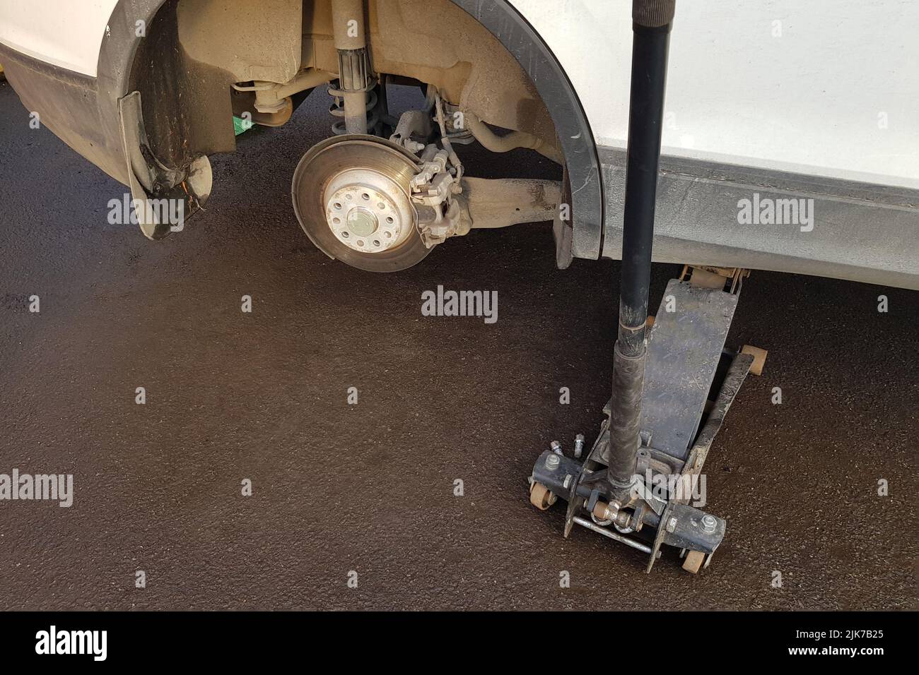 Closeup of a car lifted on jack in process of new wheel tire ...