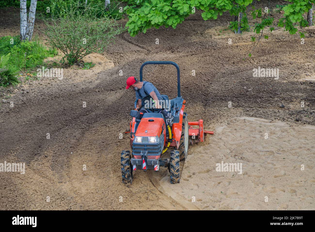 A farmer on a mini tractor loosens the soil for the lawn. Land ...
