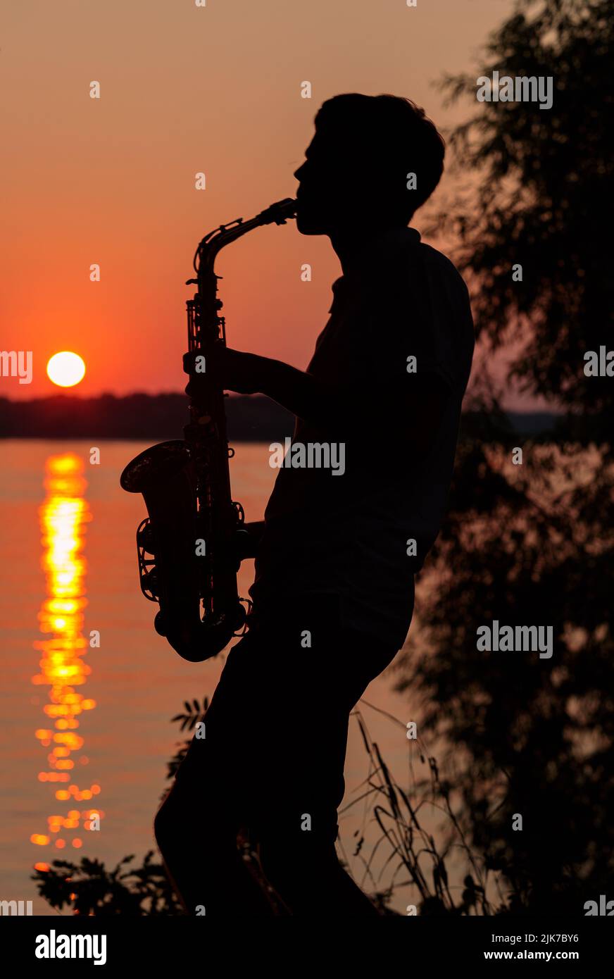 Silhouette of a young guy playing the saxophone in the evening at ...