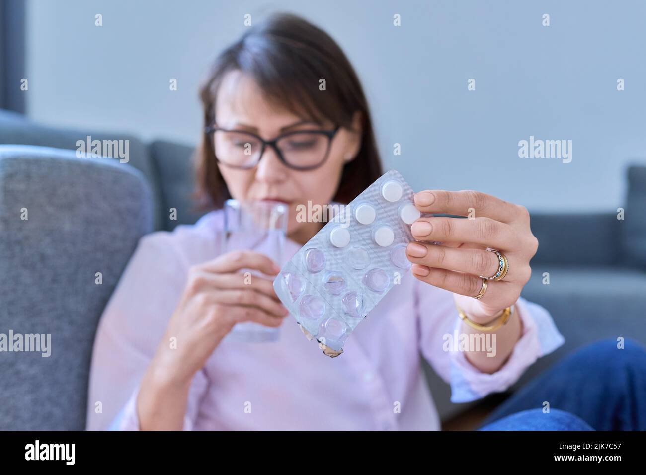 Mature sick woman taking pills with a glass of water Stock Photo - Alamy