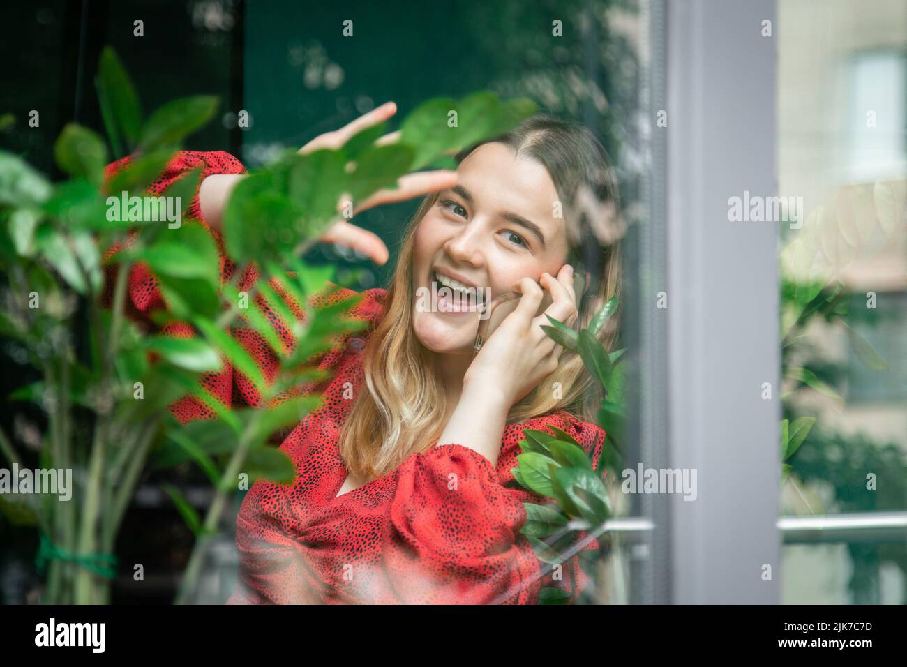 A girl talking on the phone, view from the street through the window ...