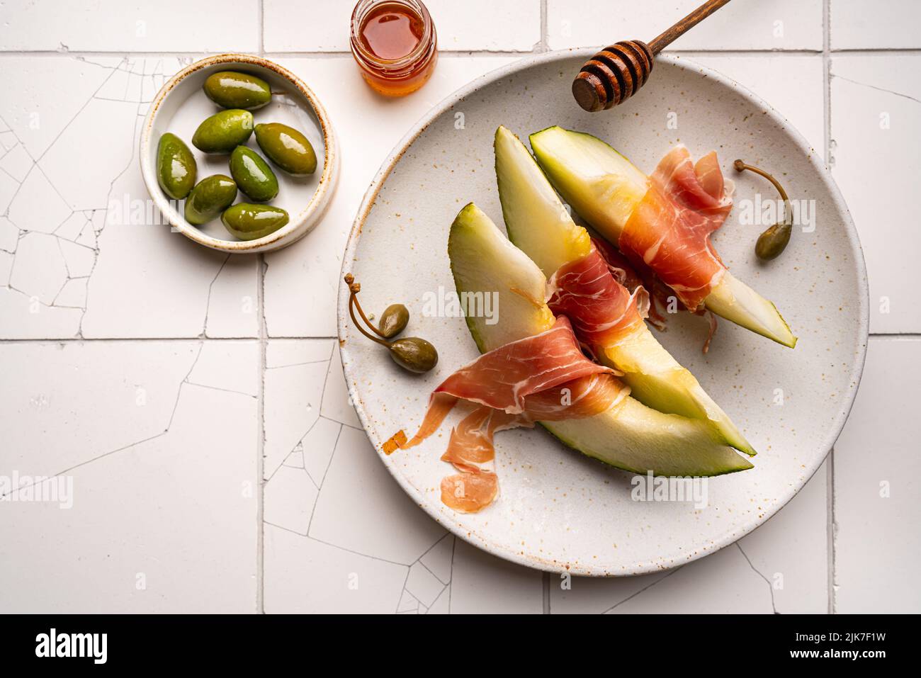 Jamon serrano, ham or prosciutto with melon and olives, a traditional ...