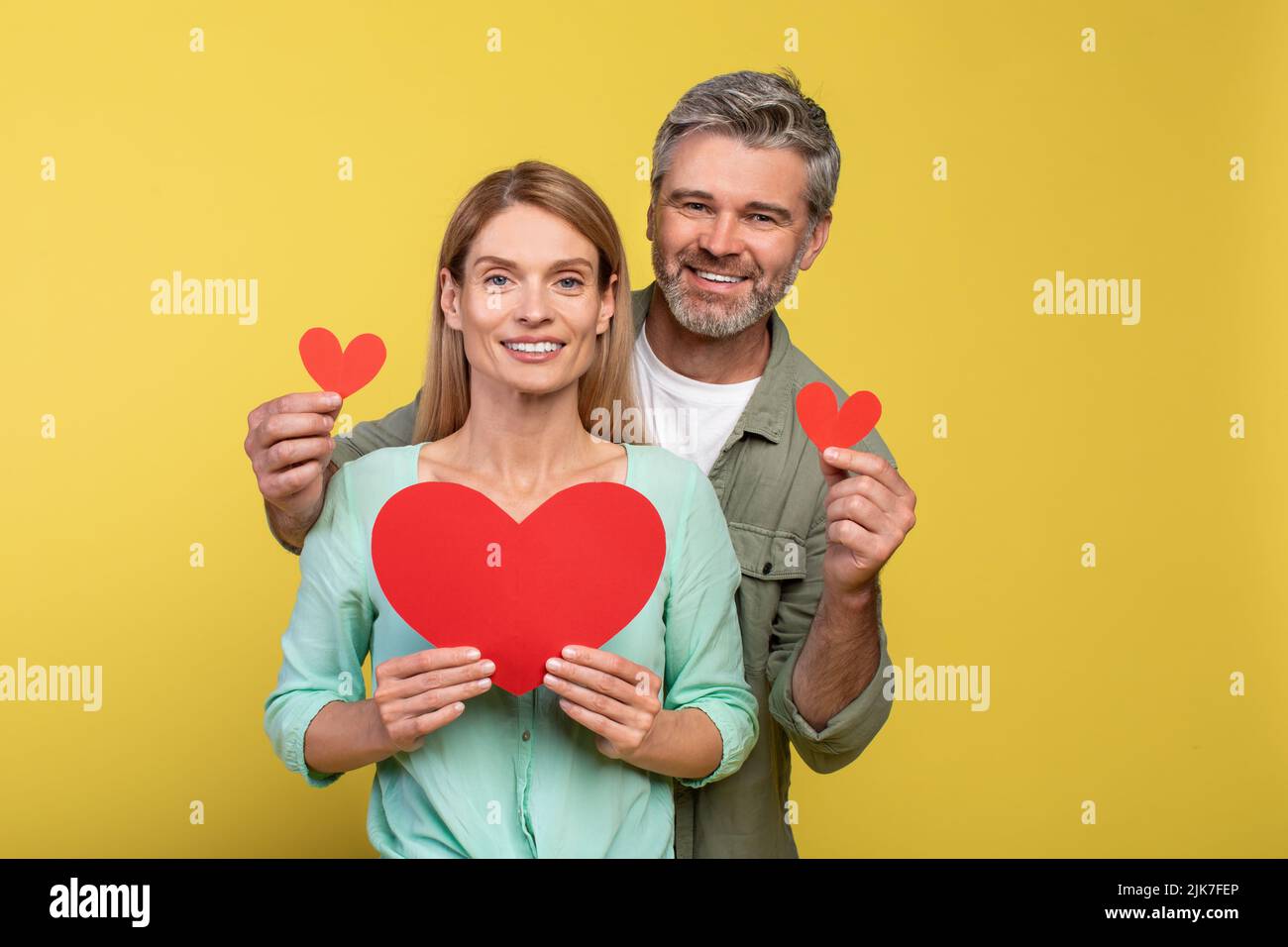 Love is in the air. Loving middle aged spouses with red paper hearts in ...