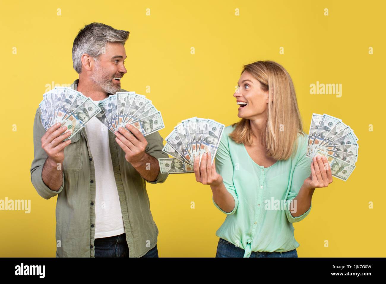 Overjoyed middle aged spouses holding bunch of money banknotes ...