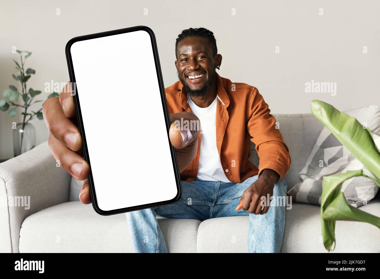 Trendy mobile phone. Happy black man holding smartphone with white ...