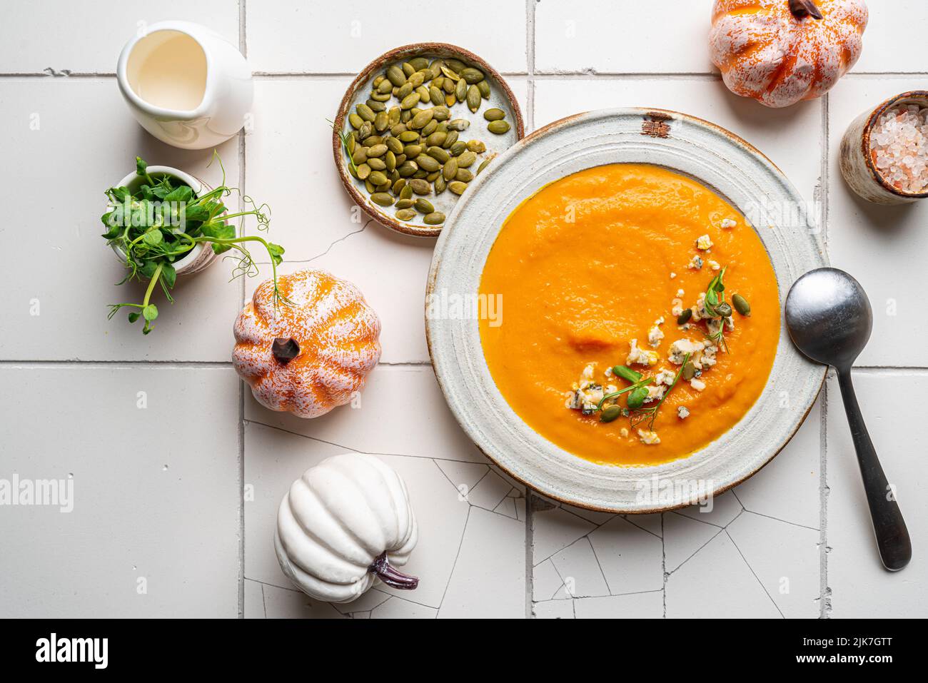 Pumpkin soup with gorgonzola cheese in white plate on white tile ...
