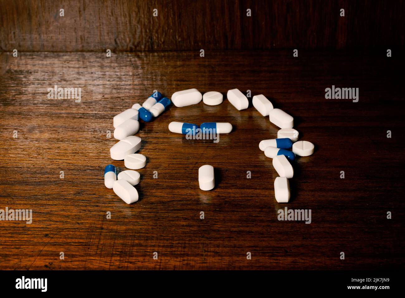 Simple pile of white and blue pills, medicines, pills stacked on brown ...