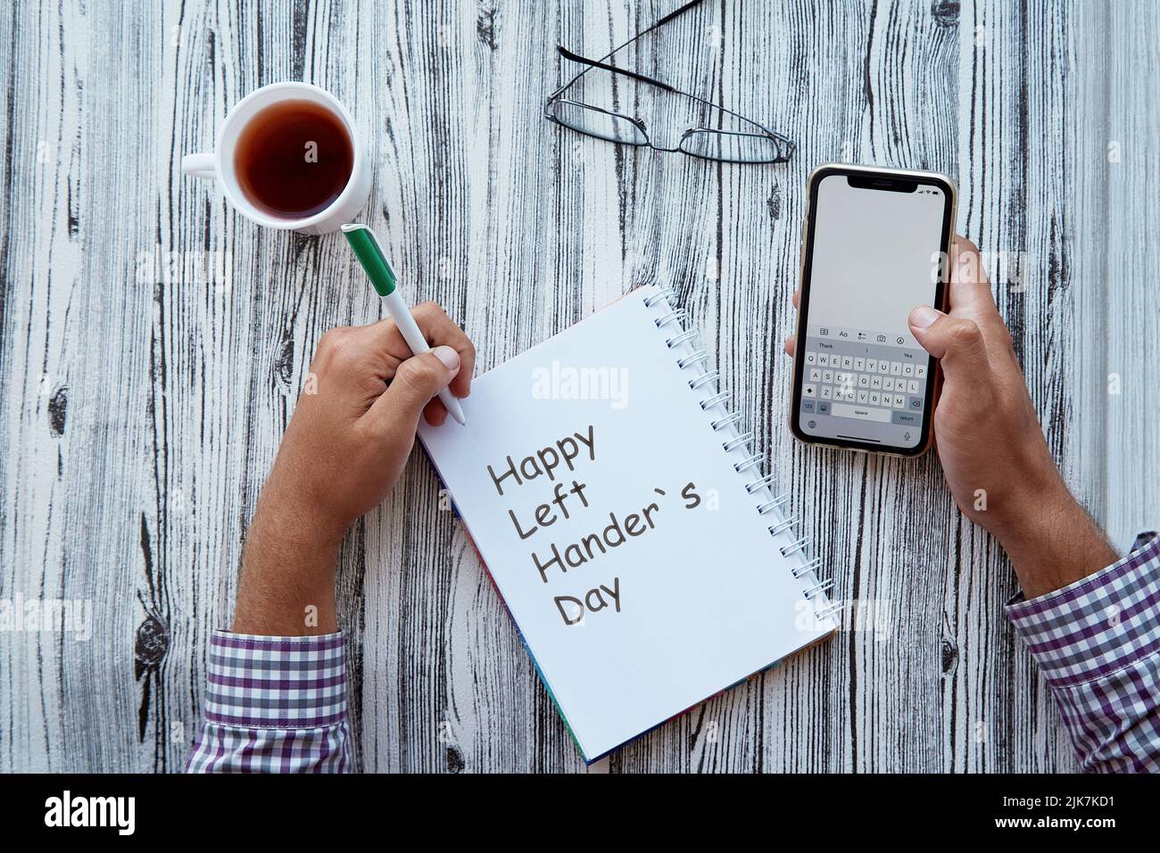 Man writes in a notebook. Happy left hander's day text writes by his ...