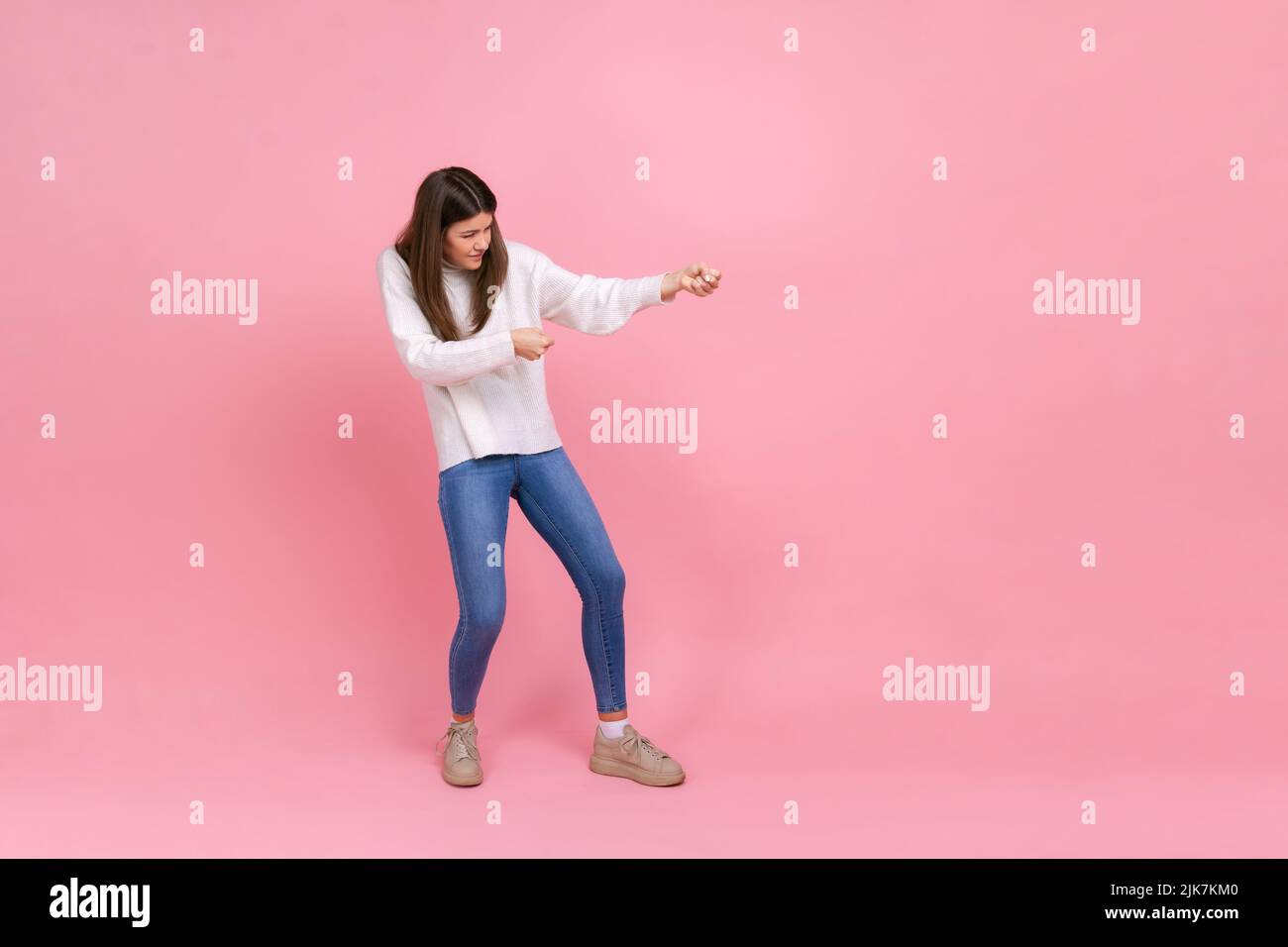 Full length portrait of girl pulling invisible rope with effort, using ...