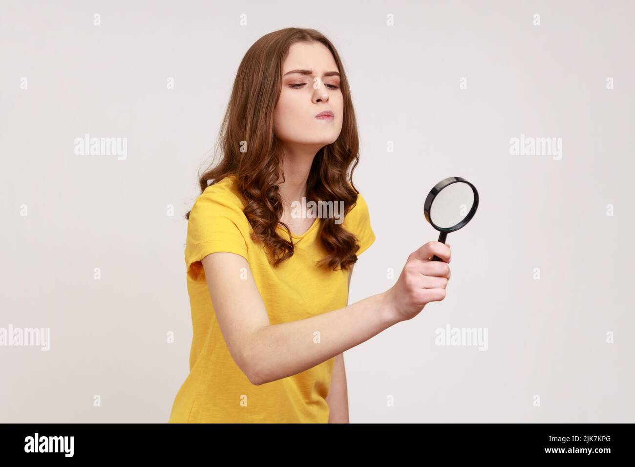 Young attractive curious female with brown hair looking through ...
