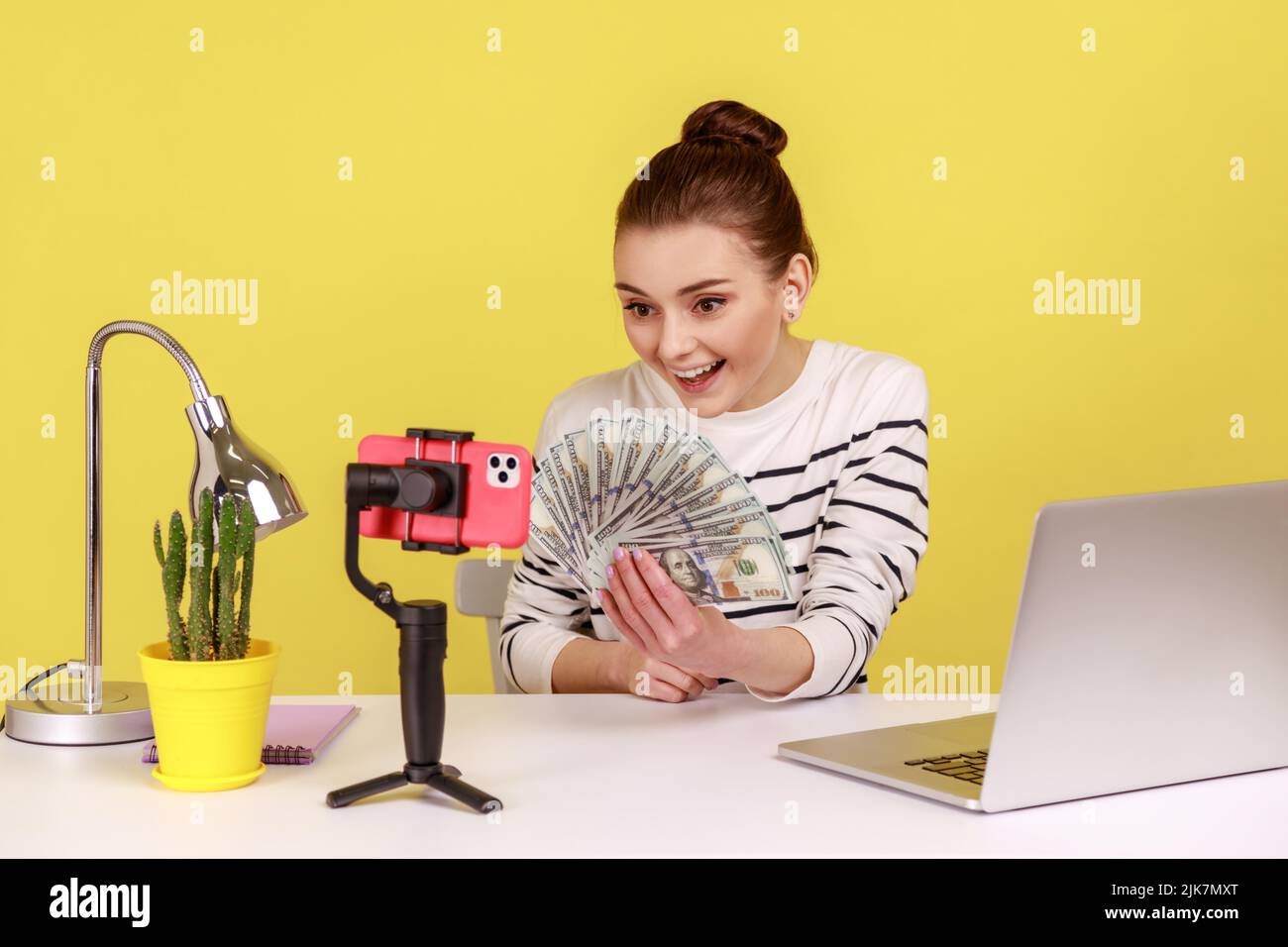 Excited woman holding dollar banknotes, recording video to subscribers ...
