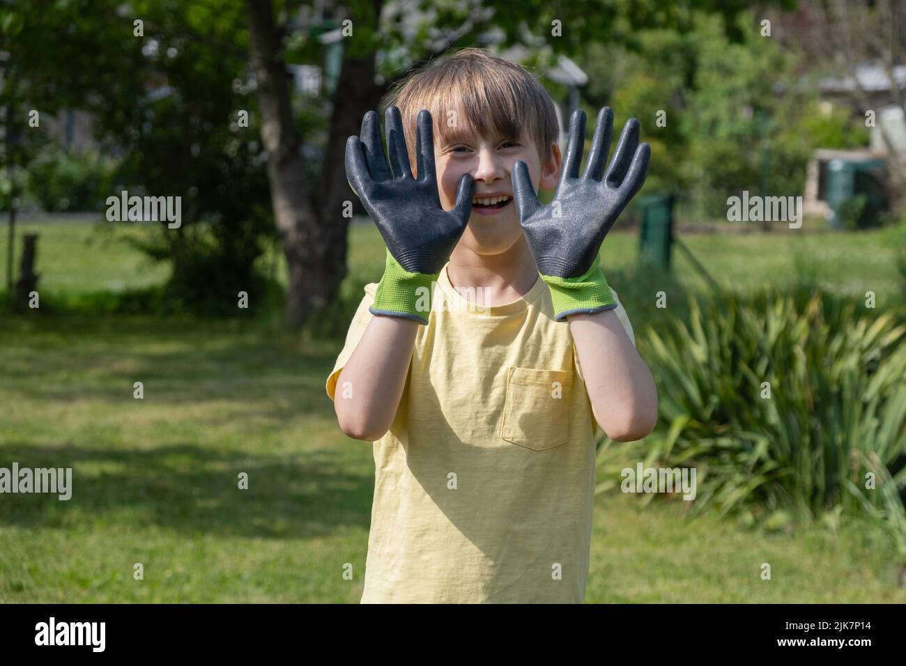 Boy in home garden wearing gardening gloves Stock Photo - Alamy