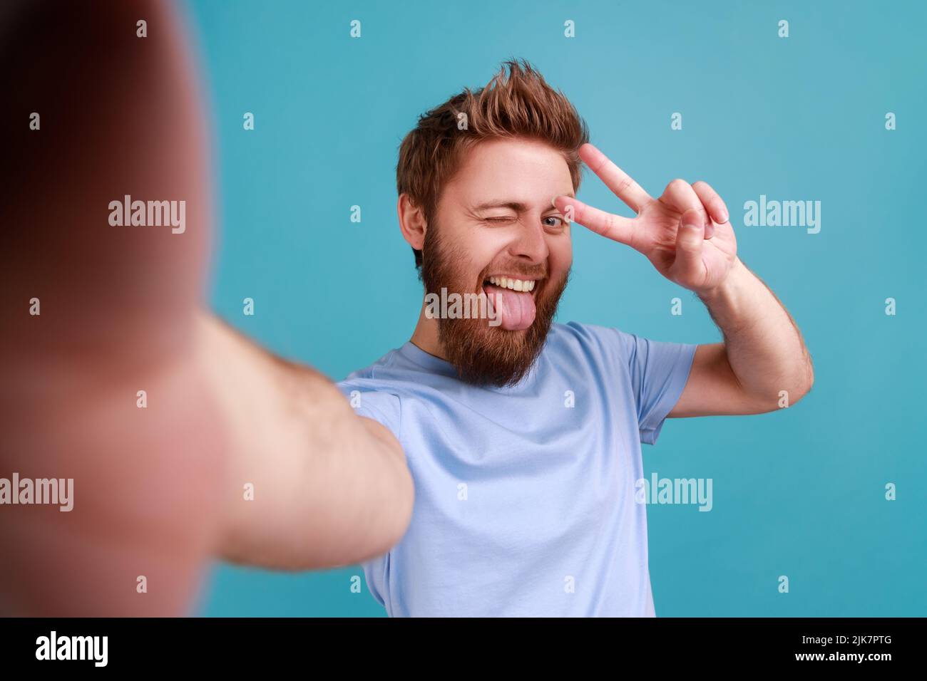 Delighted positive optimistic bearded man taking selfie, looking at ...