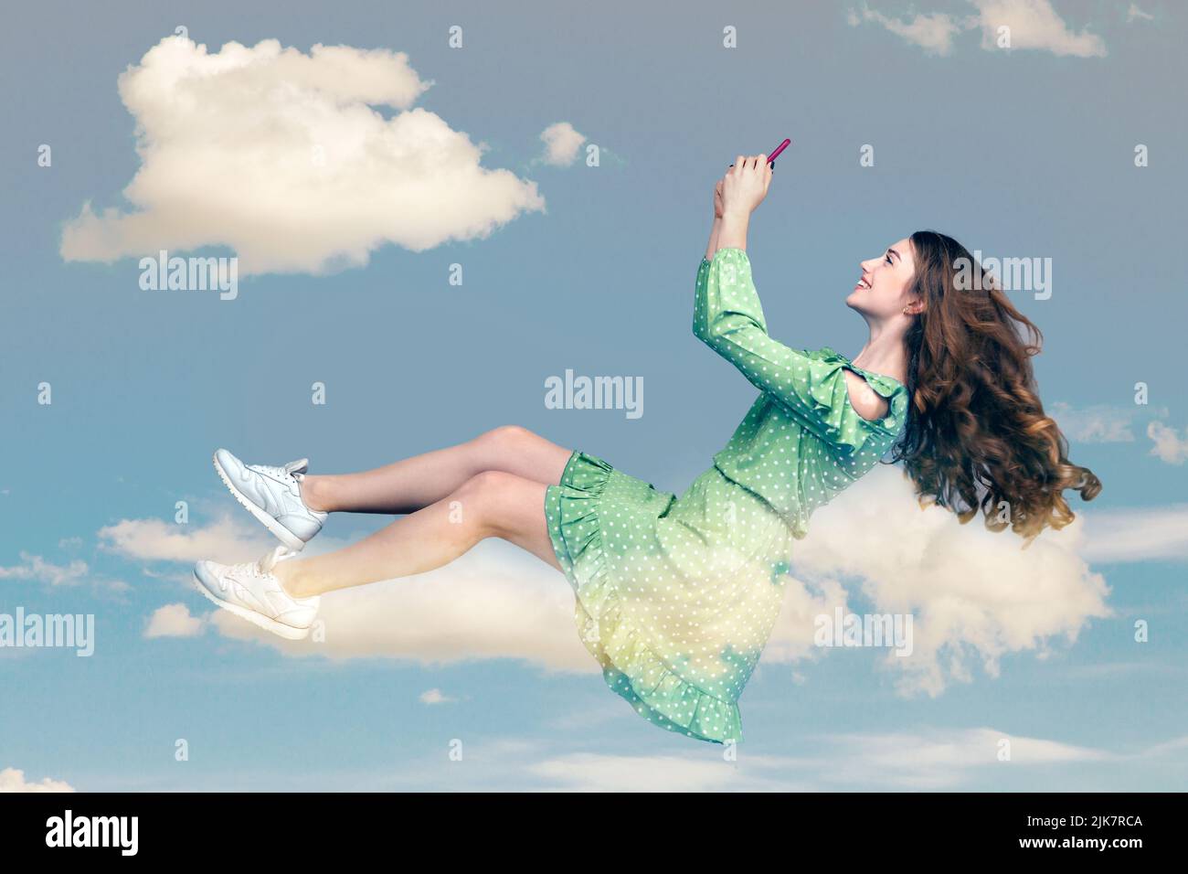 Hovering in air. Happy girl in dress levitating with mobile phone, reading message chatting ...