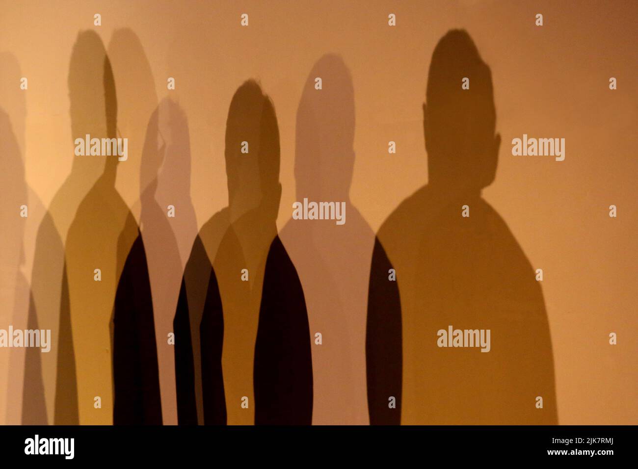 A group of men cast a variety of shadows on a wall Stock Photo - Alamy