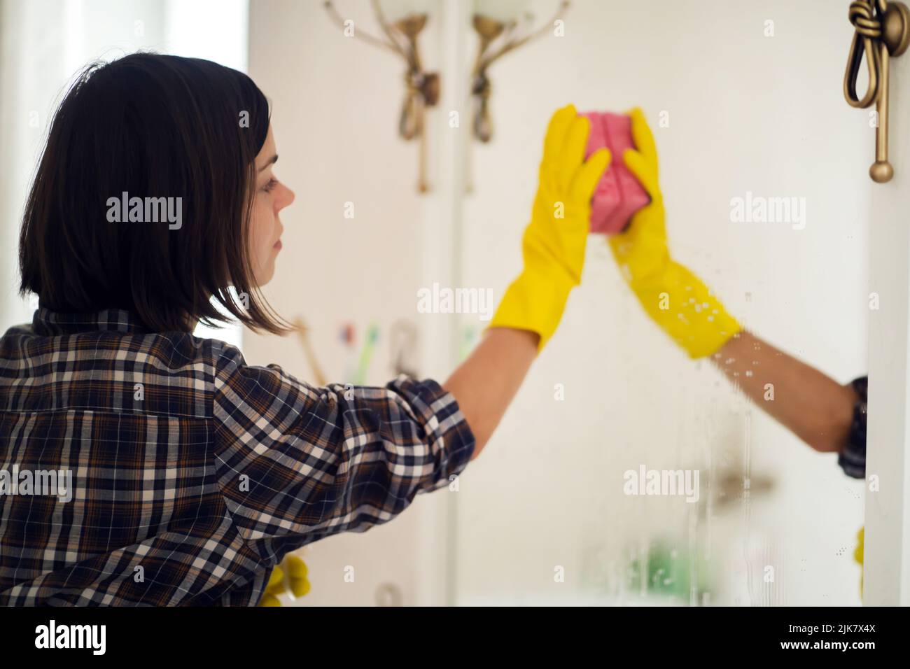 Girl is washing the mirror with a detergent Stock Photo - Alamy