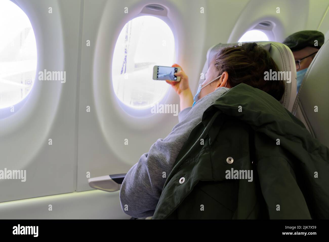 Woman taking picture through airplane window. Taking photo on airplane ...