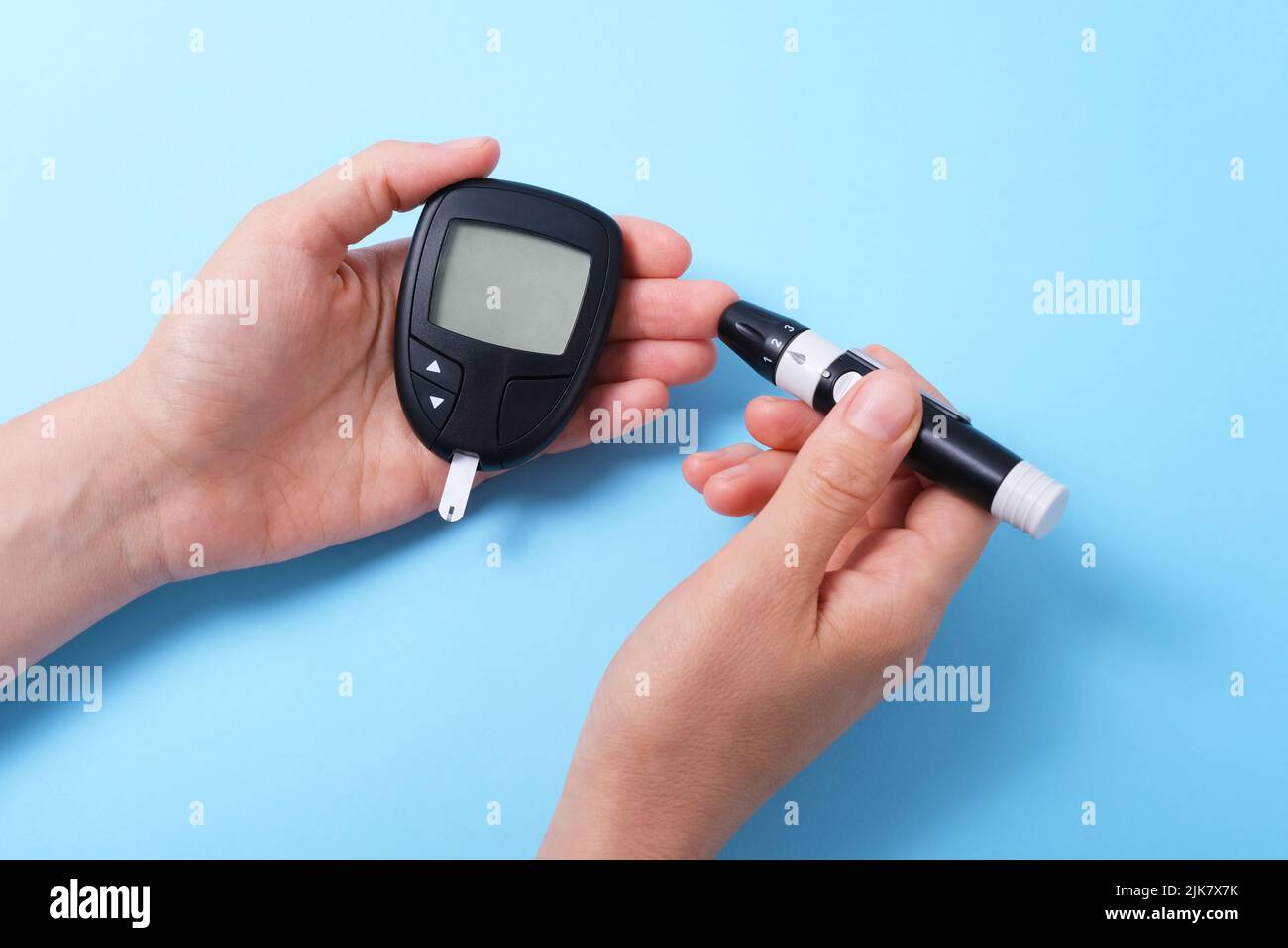 Woman using glucometer, checking blood sugar level. Diabetes concept on ...