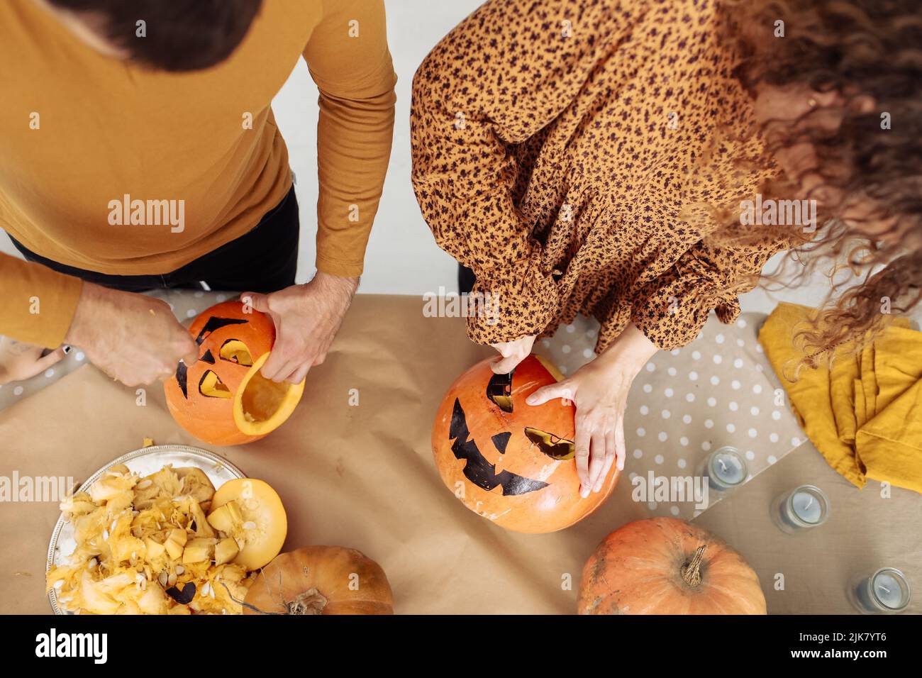 Young couple man and woman on kitchen at home making jack-o'-lantern ...