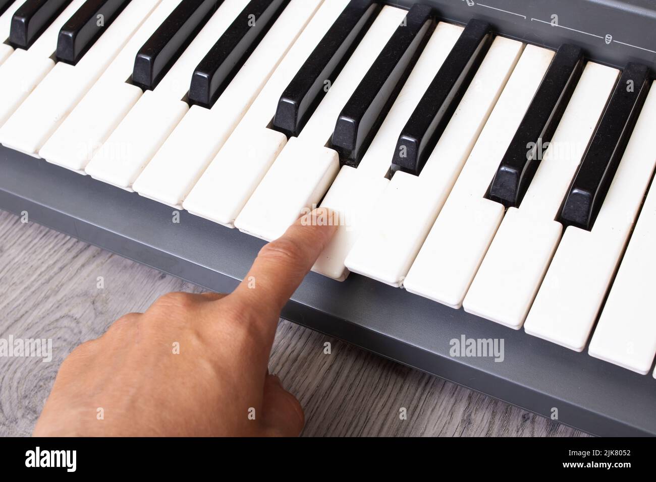 Finger presses the white piano key close up Stock Photo - Alamy