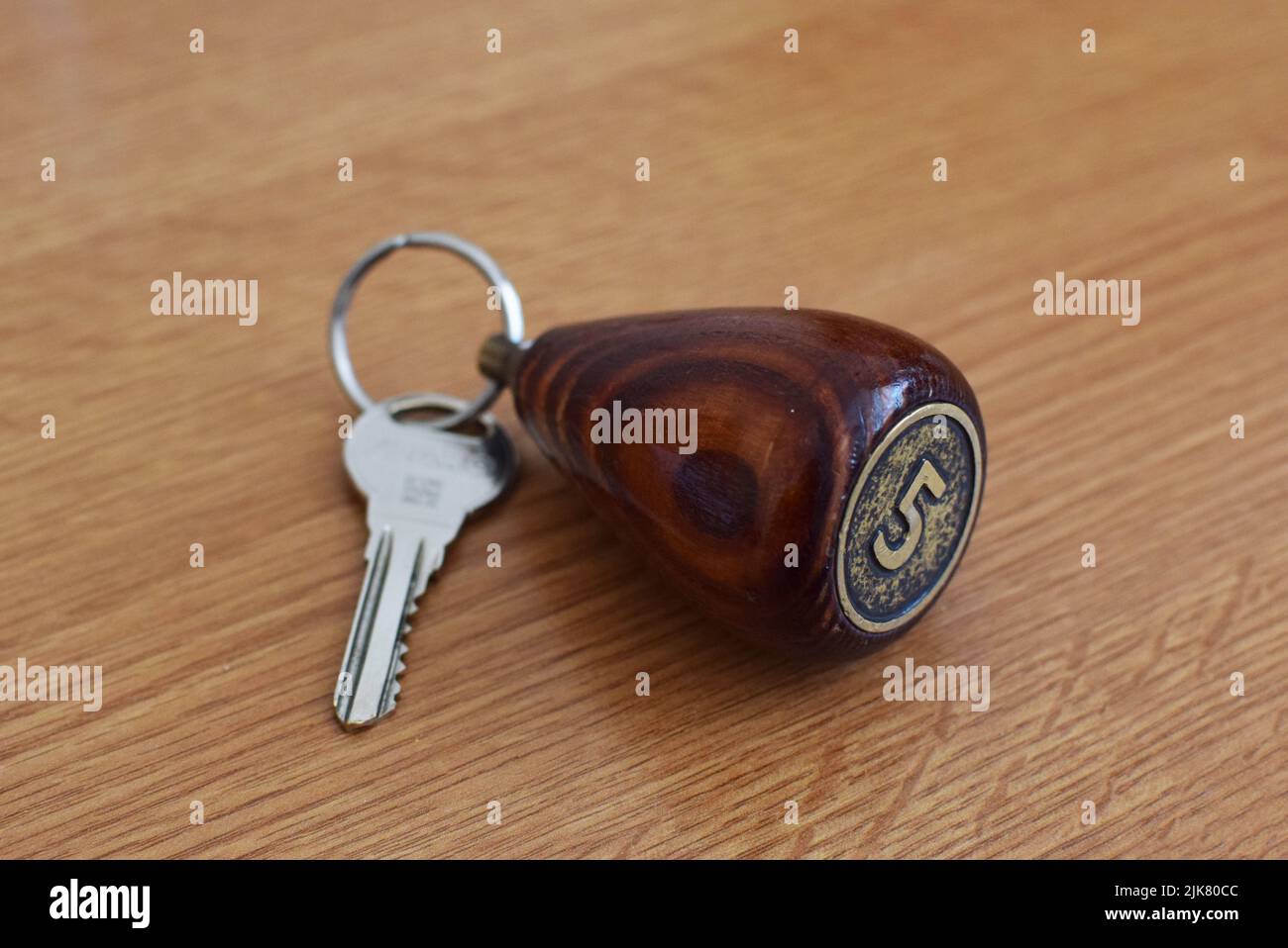 Hotel key with room number on wooden reception desk. Selective focus ...