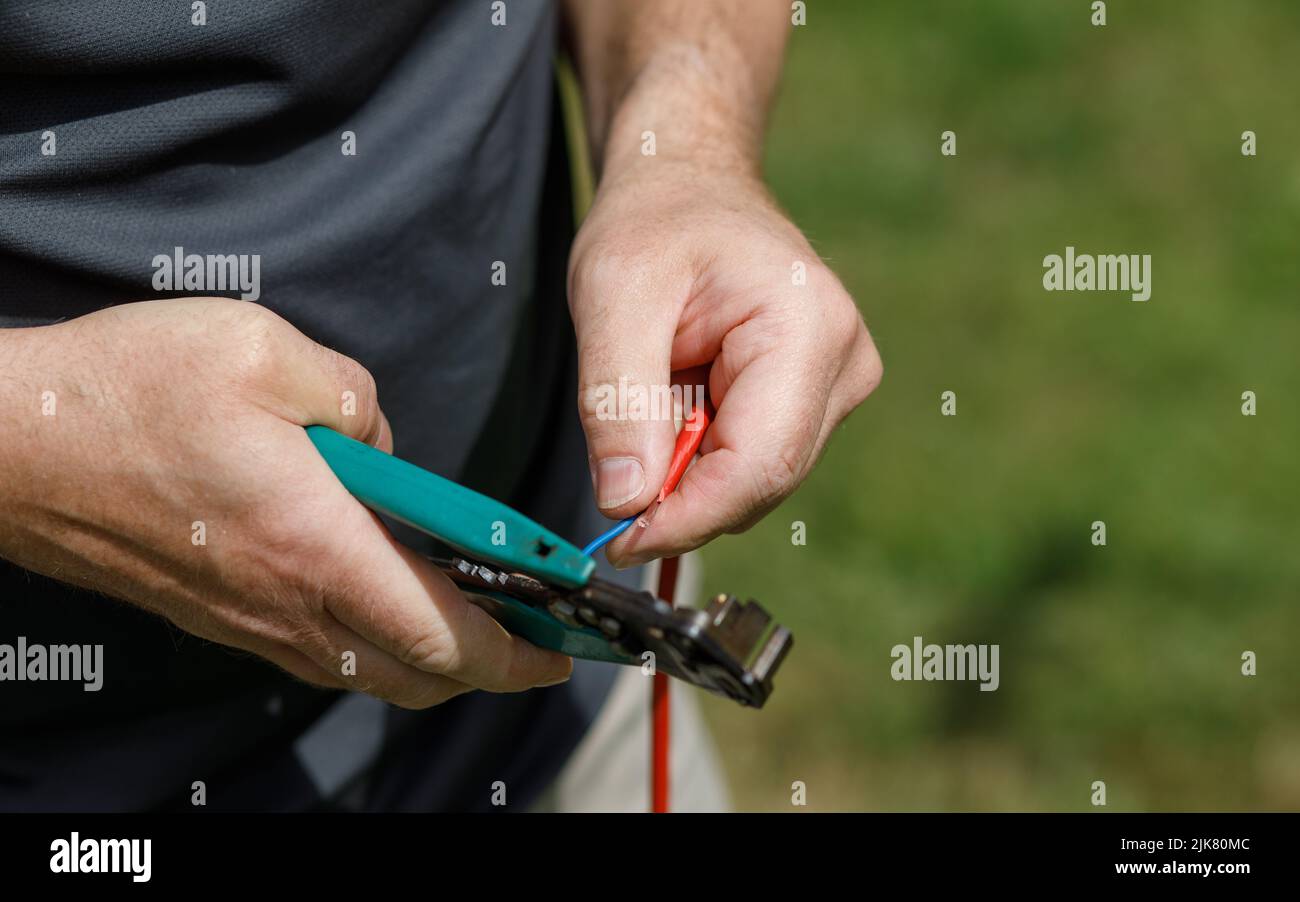 Wire cutters, held in hands cutting an electrical cable Stock Photo - Alamy