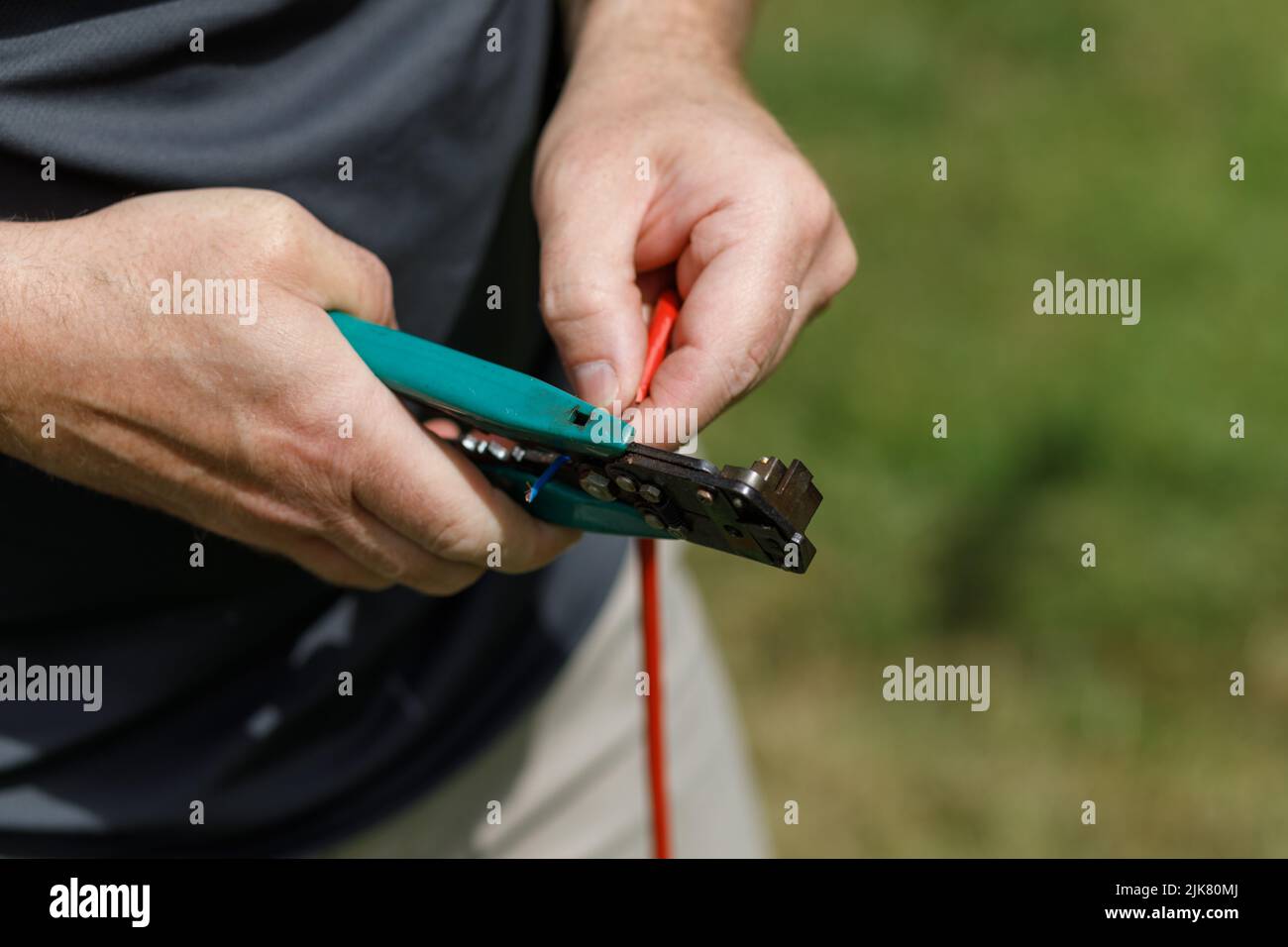 Wire cutters, held in hands cutting an electrical cable Stock Photo - Alamy