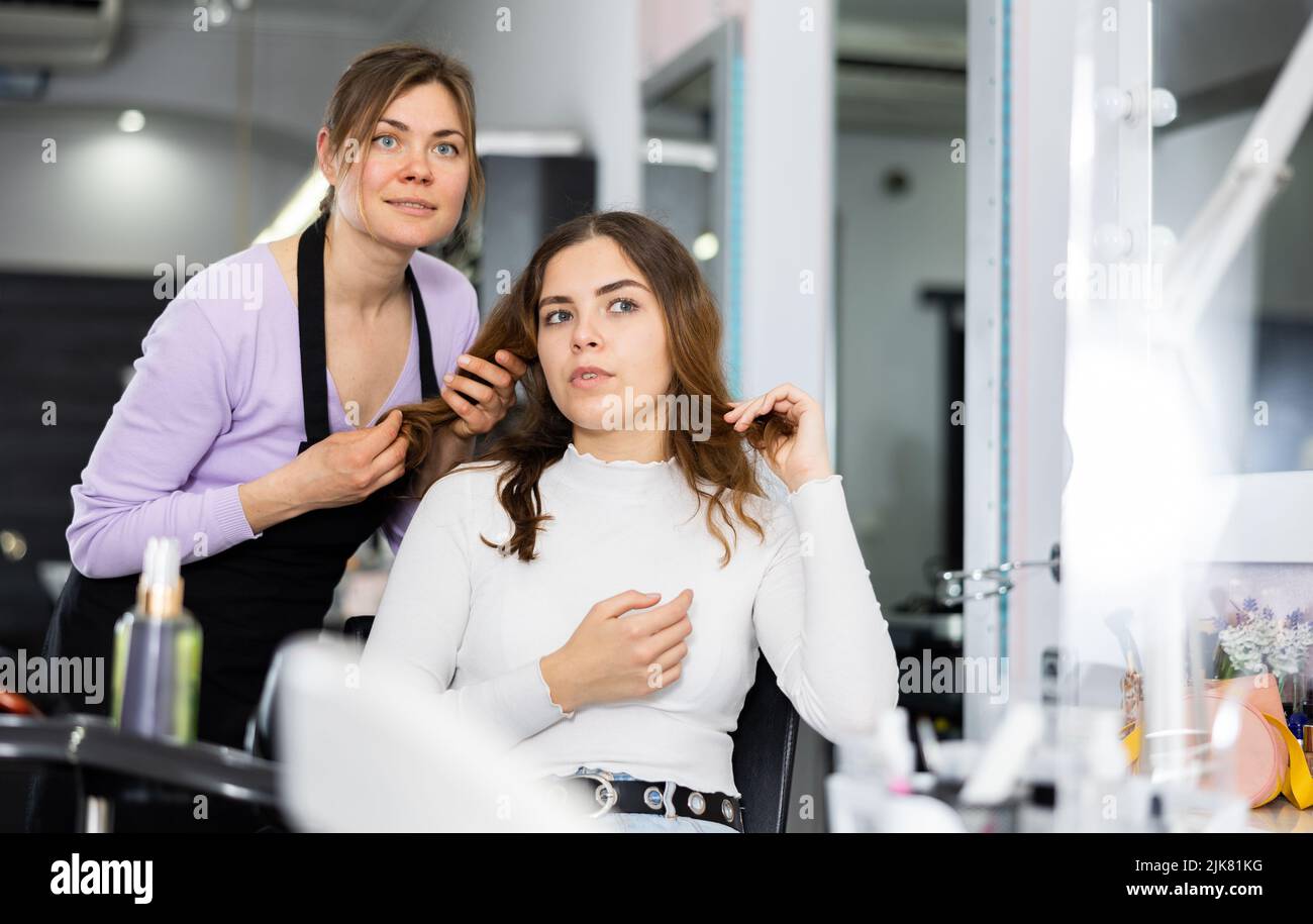 Woman hair stylist discussing new hairdo with young female customer ...