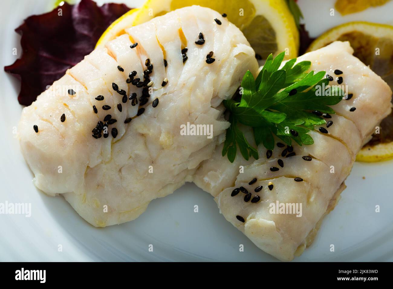 Cod prepared on steam, served at plate with greens and lemon Stock ...