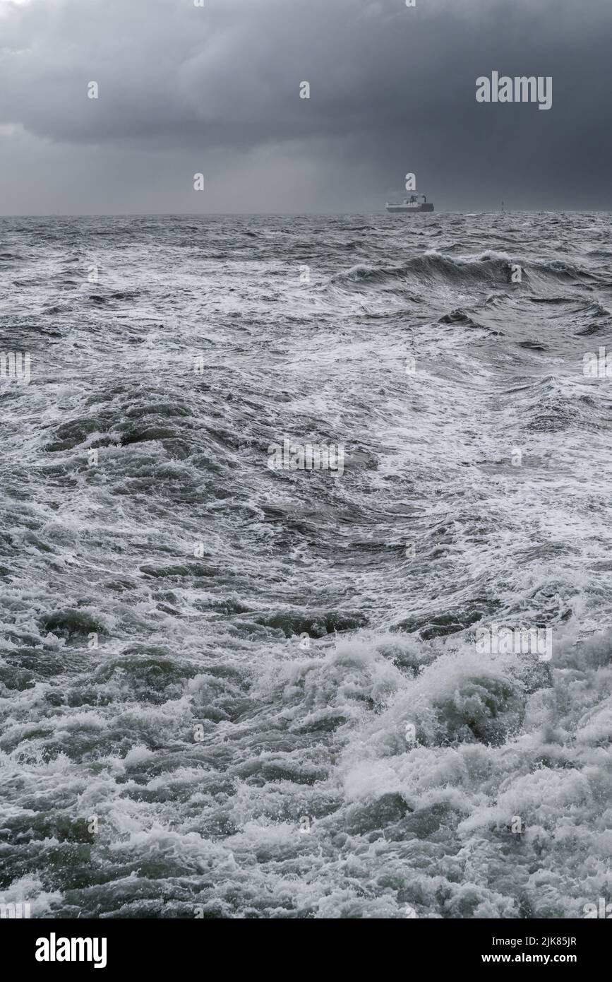 Vertical shot of very rough sea with black dramatic clouds in the sky ...