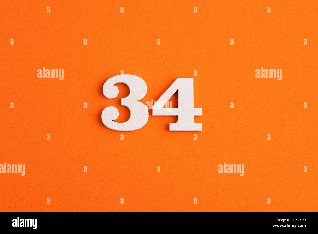 White wooden number 34 on eva rubber orange background Stock Photo - Alamy